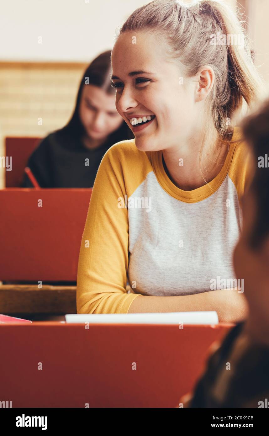 Smiling girl sitting in classroom. Female student smiling during a ...