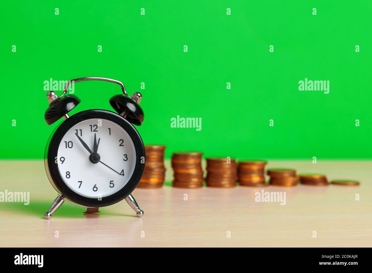 Time is money, table clock with coins Stock Photo - Alamy