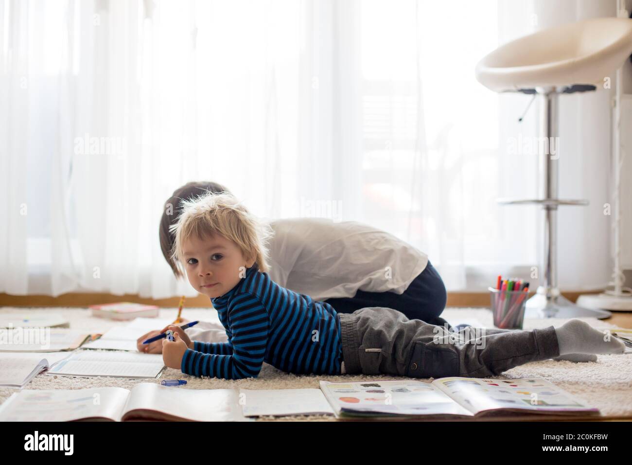 Child, doing school work on the floor at home while in quarantene, kid ...