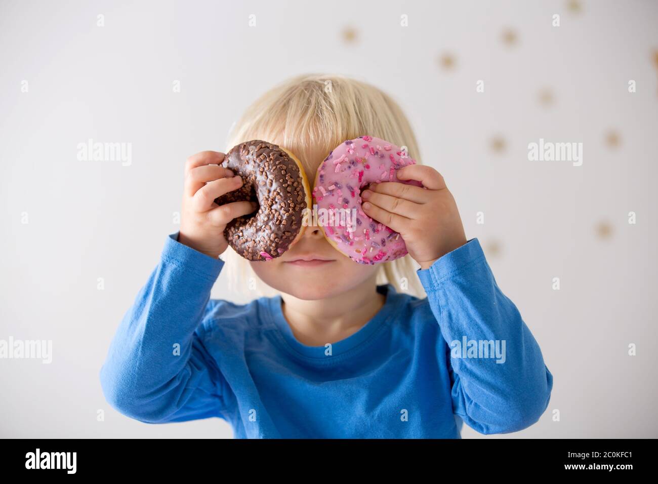 Cute sweet blonde child, playing and eating donuts at home Stock Photo ...