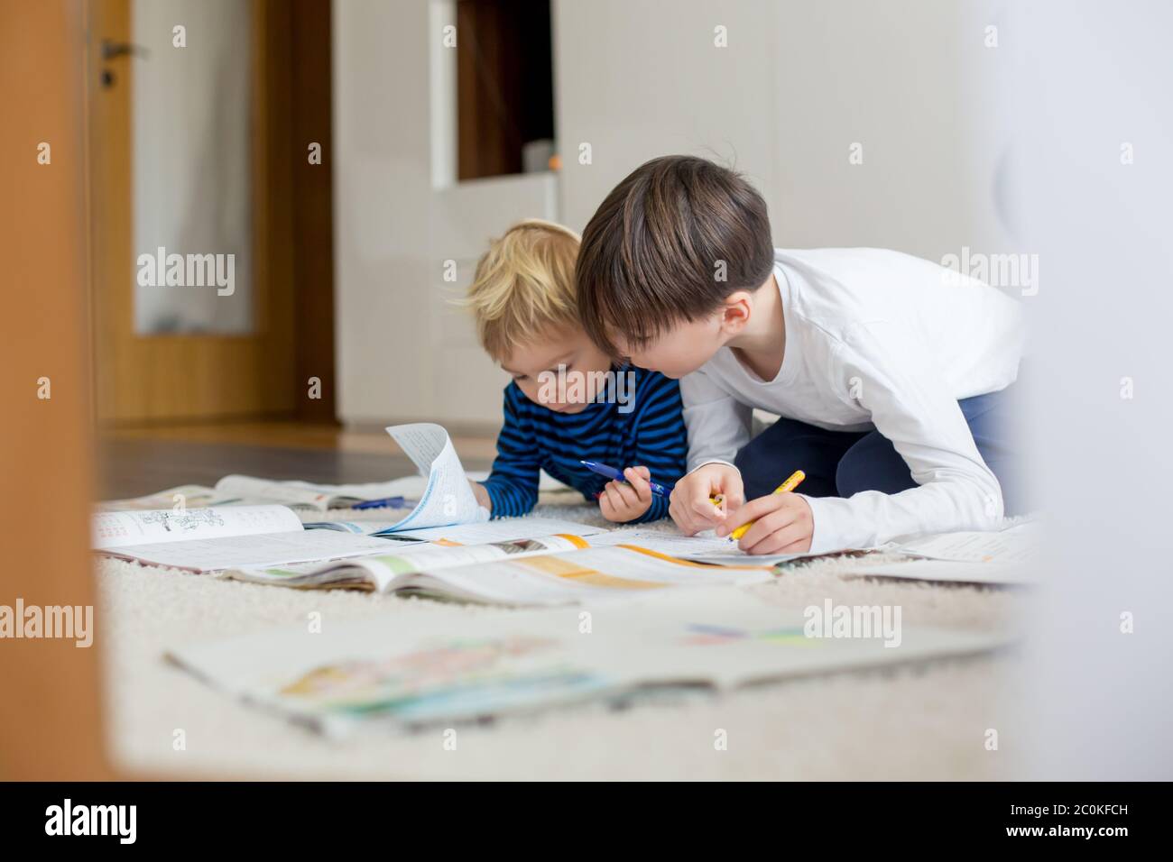 Child, doing school work on the floor at home while in quarantene, kid ...
