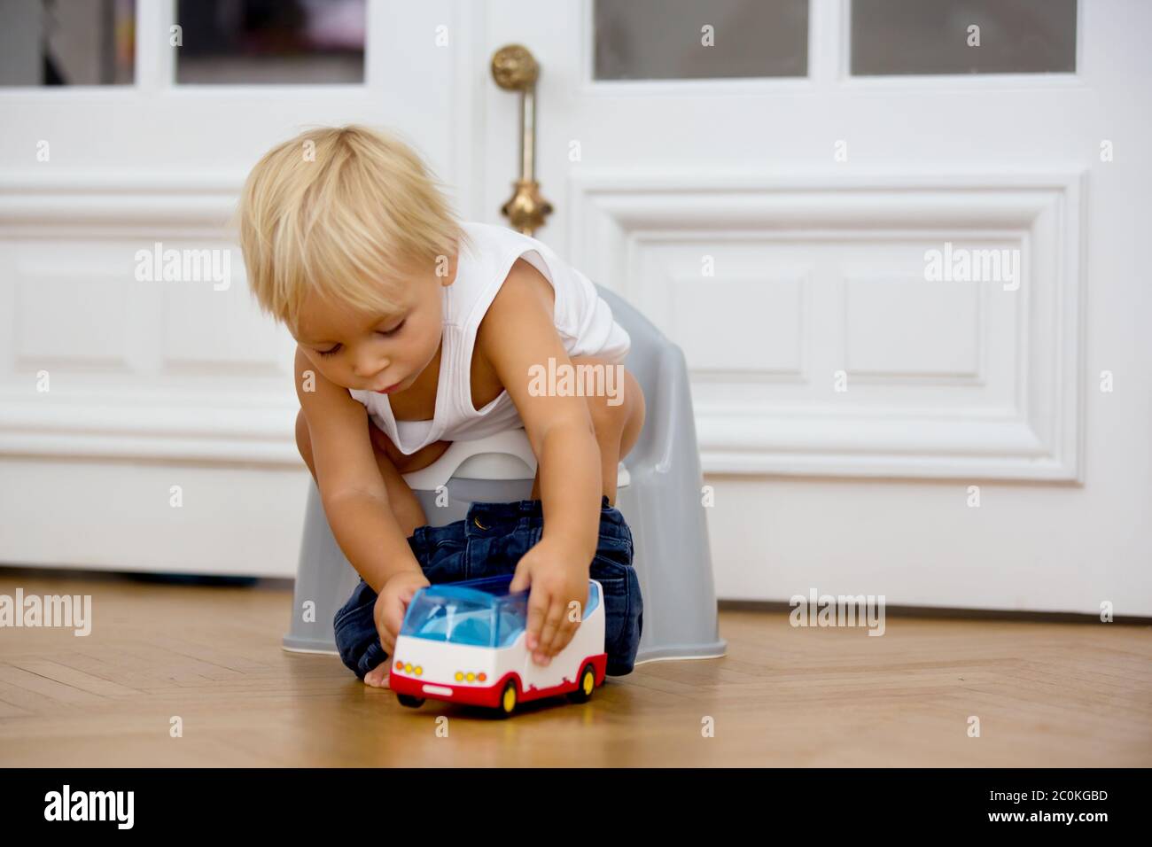 Infant child baby boy toddler sitting on potty, playing with toys in ...