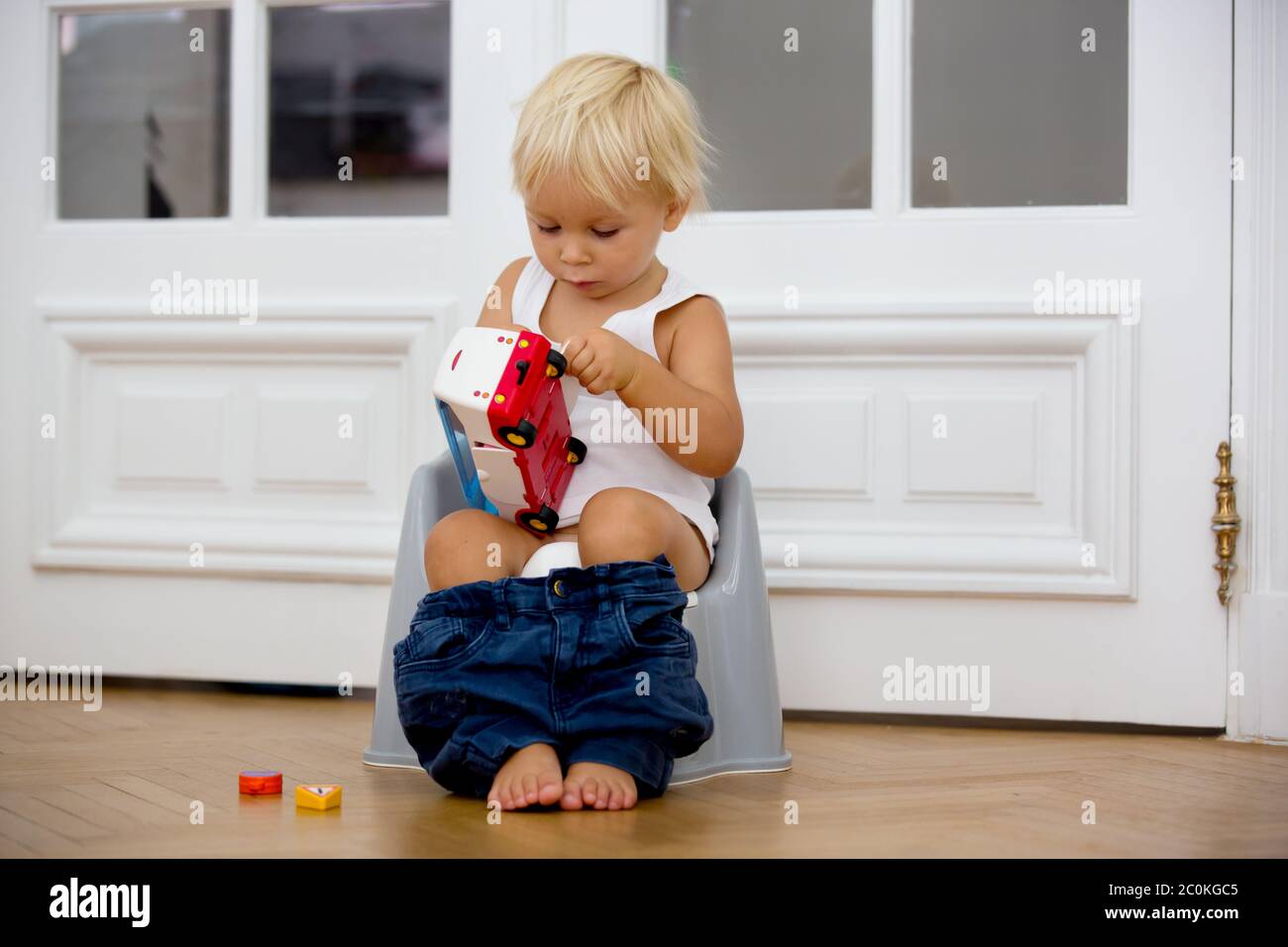 Infant child baby boy toddler sitting on potty, playing with toys in ...