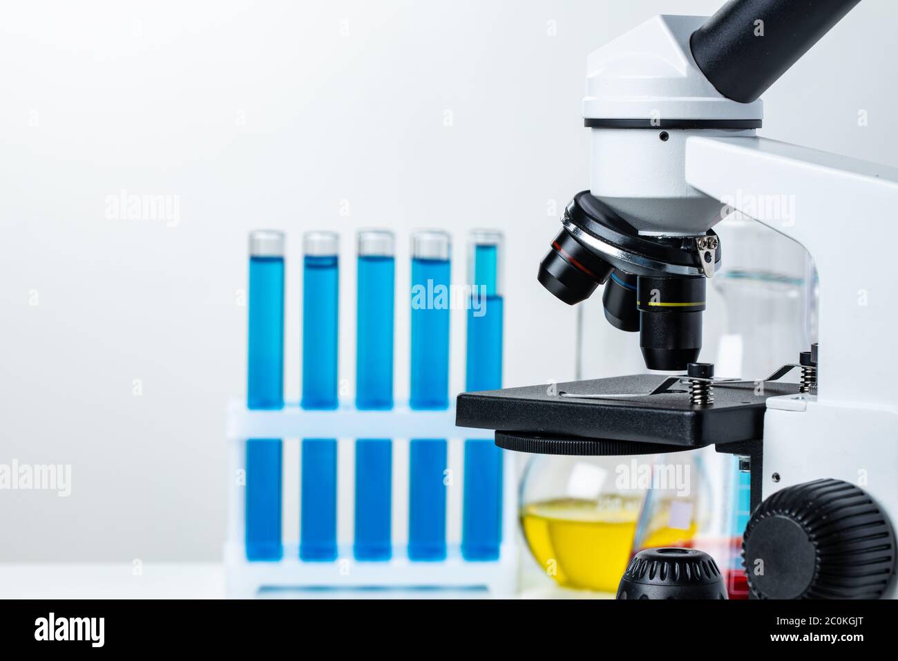 Close up of laboratory microscope with set of test tubes with blue ...