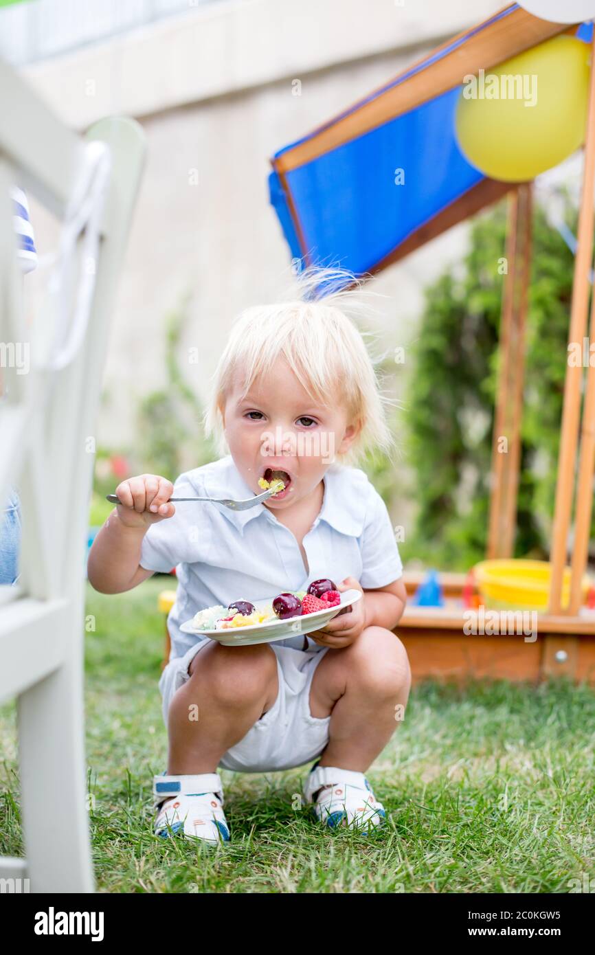 Little boy celebrating his birthday in home's garden with big colorful ...