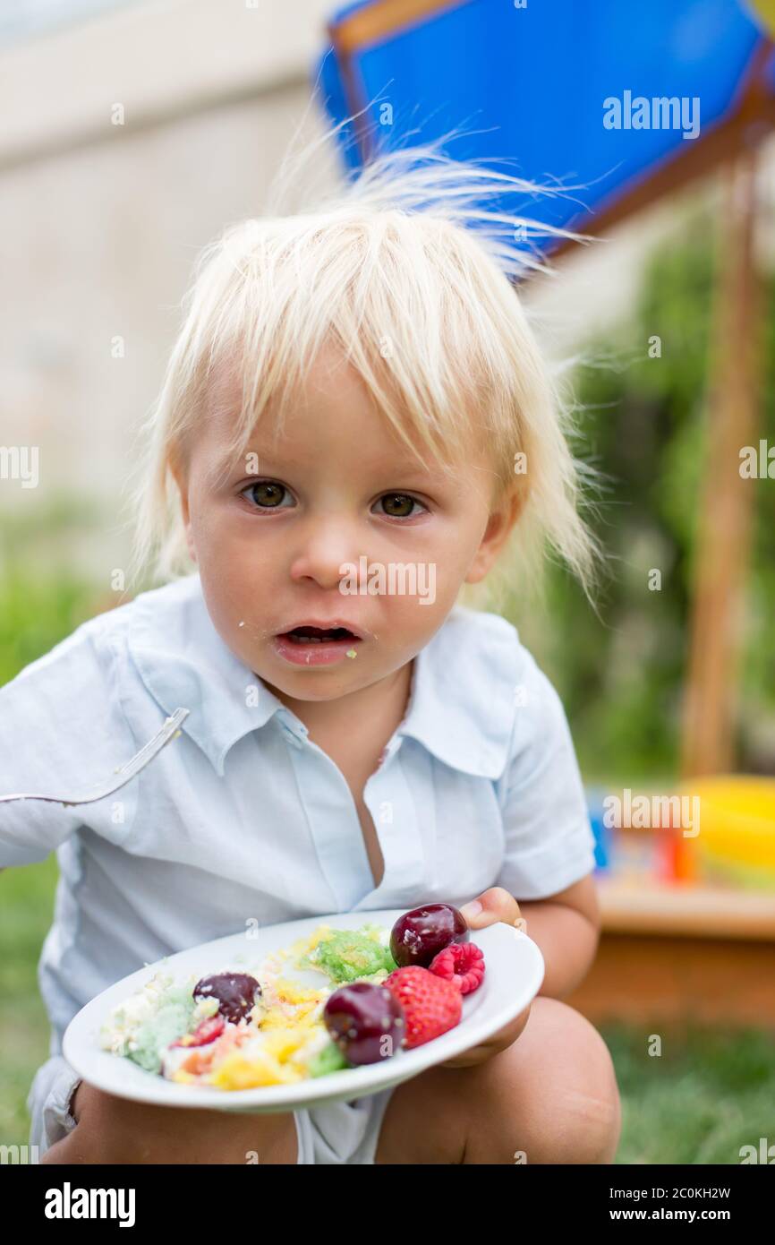 Little boy celebrating his birthday in home's garden with big colorful ...
