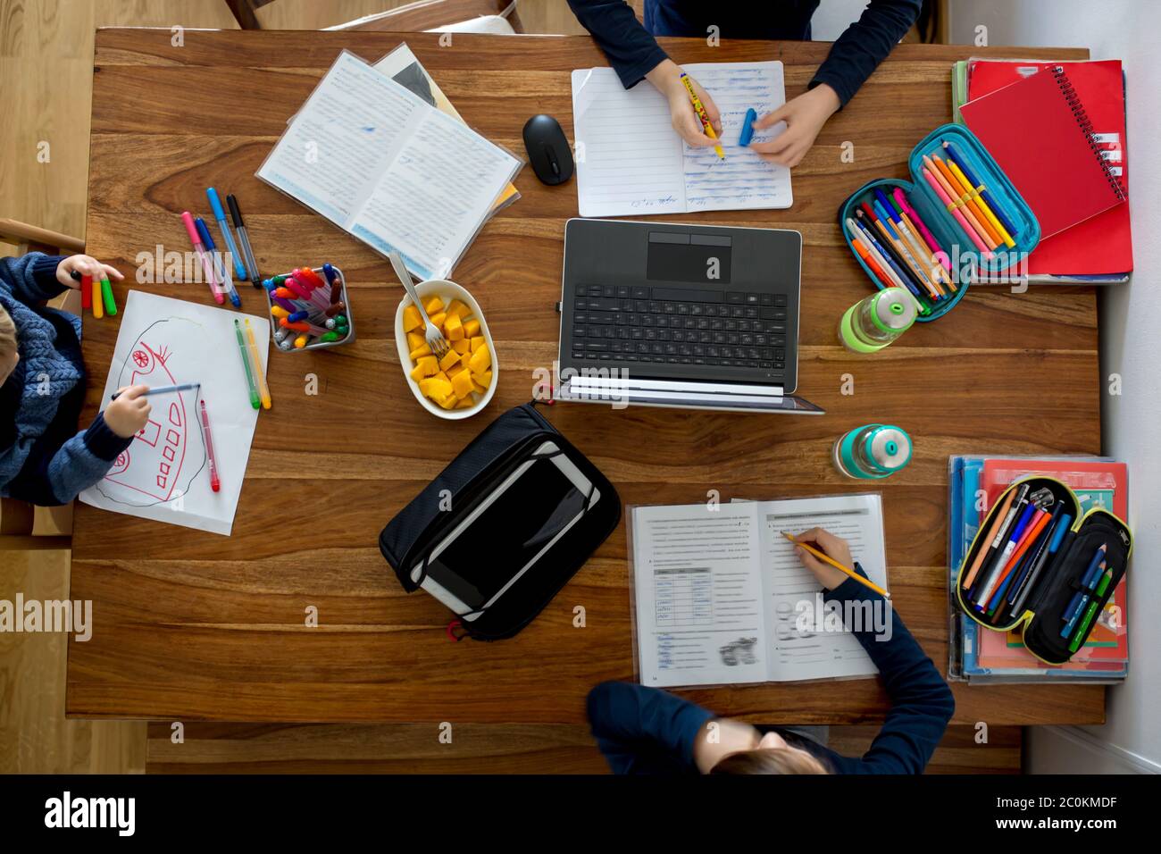 Three children, sitting around the table, writing school tasks while ...