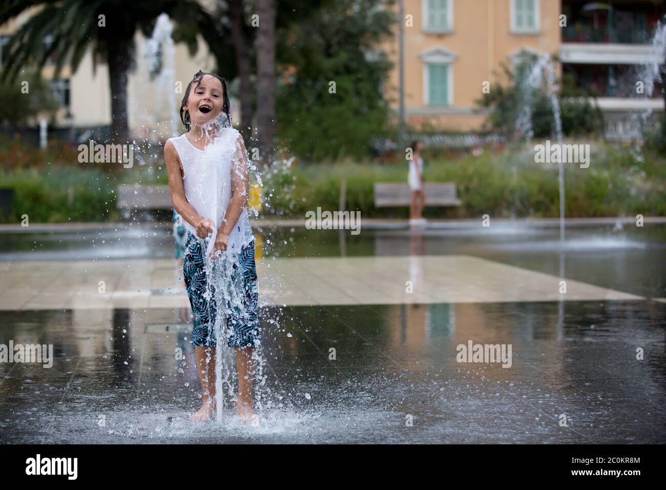 Cute preschool boy playing on a jet fountains with water splashing ...