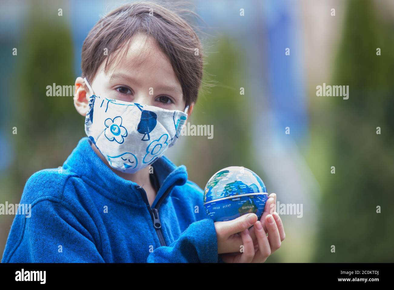 School child, holding small globe, looking sad at the world during ...