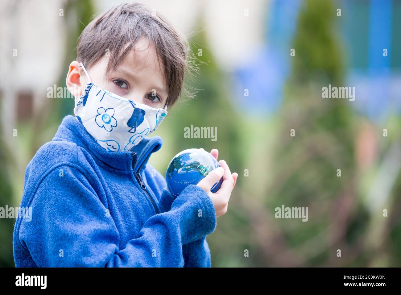 School child, holding small globe, looking sad at the world during ...