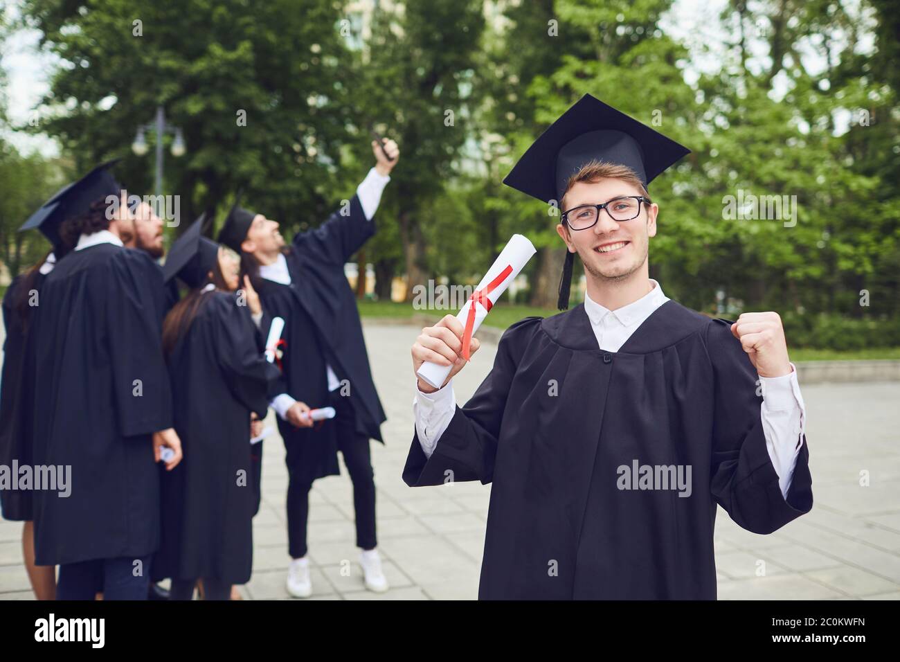 Man graduate is smiling against the background of university graduates ...