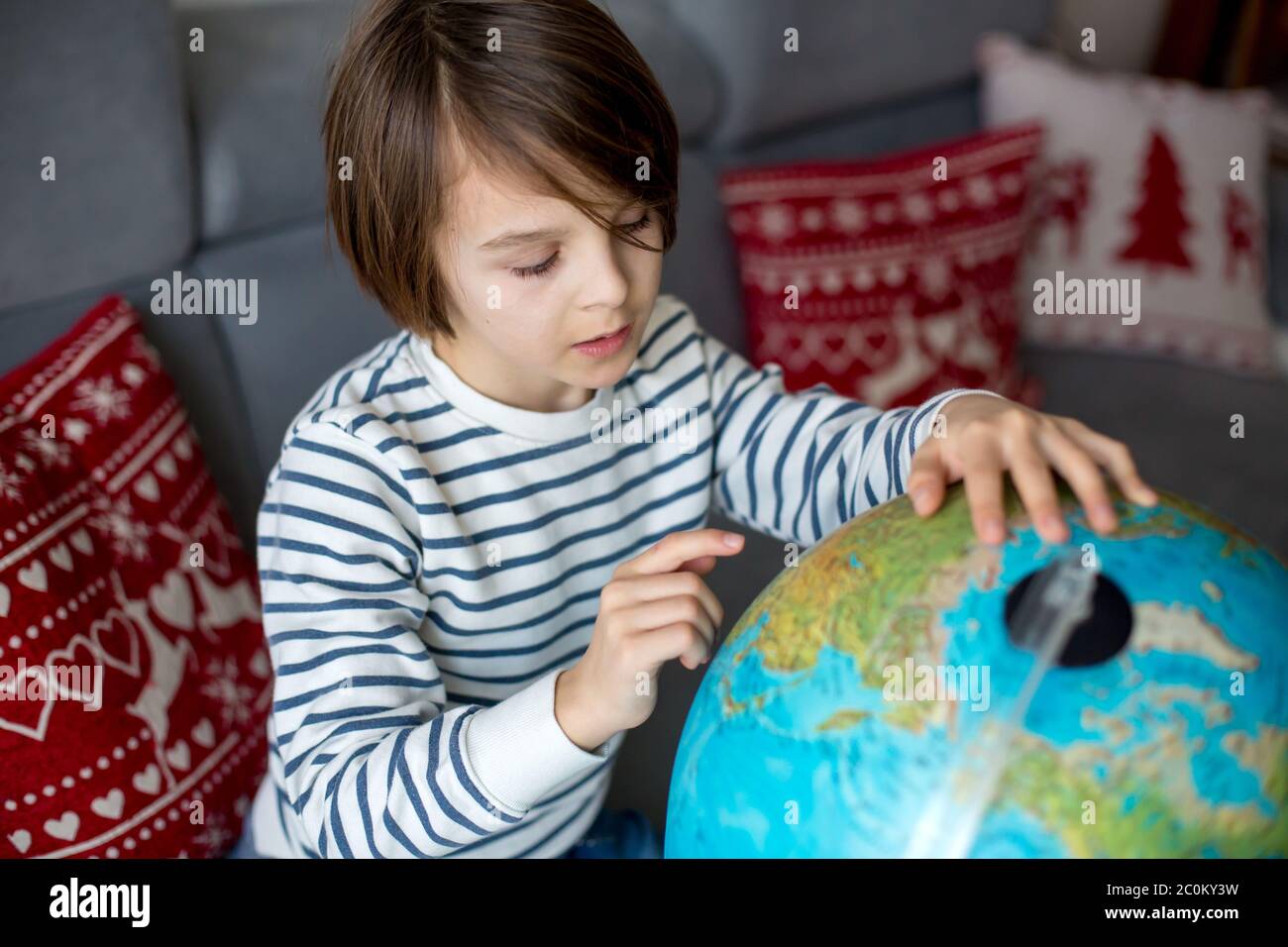 Little child, looking at illuminated globe, exploring the world ...