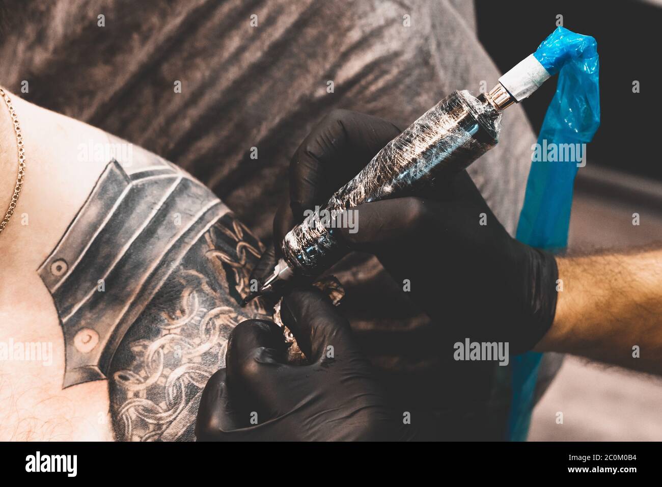 Tattoo salon. The tattoo master is tattooing a man on his shoulder ...