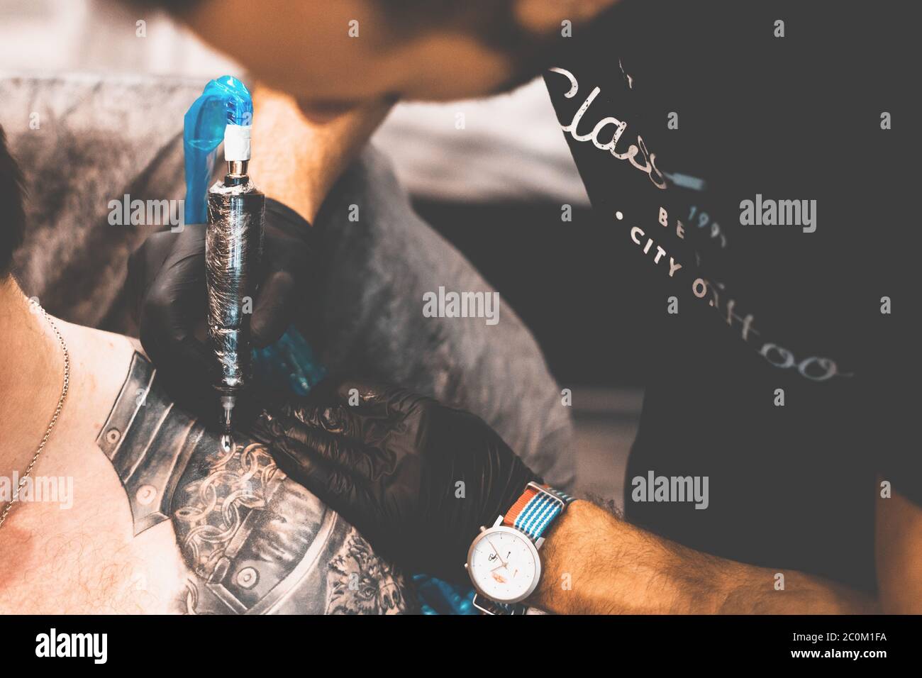 Tattoo salon. The tattoo master is tattooing a man on his shoulder ...