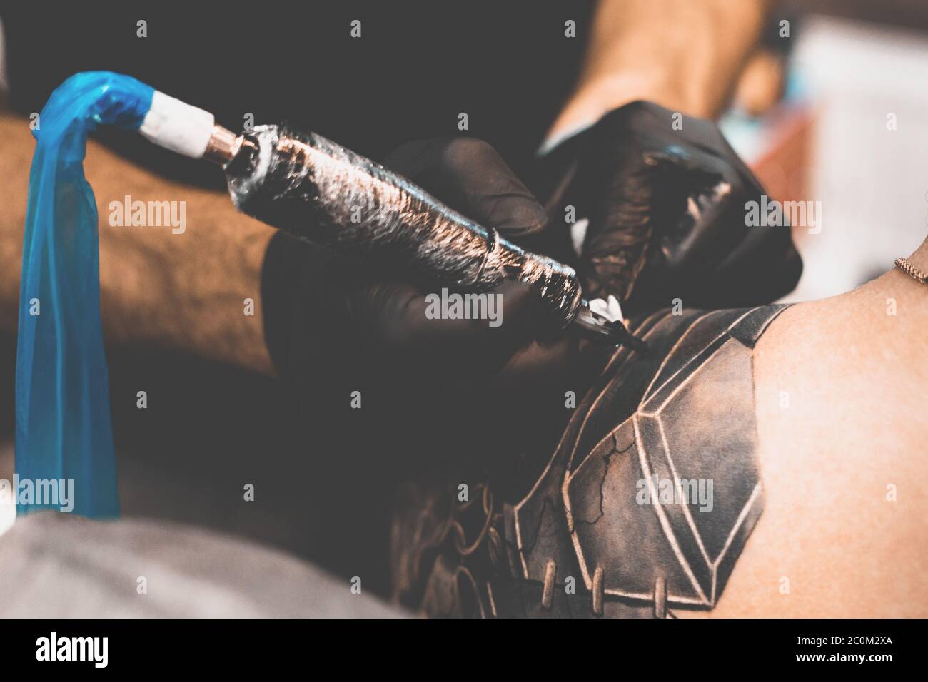 Tattoo salon. The tattoo master is tattooing a man on his shoulder ...