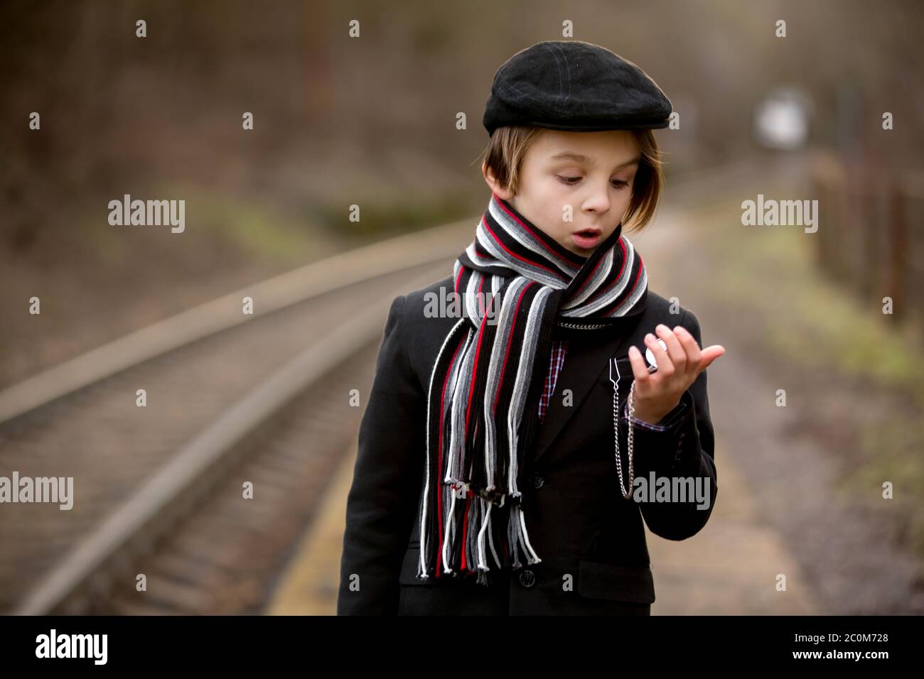 Adorable boy on a railway station, waiting for the train with vintage ...