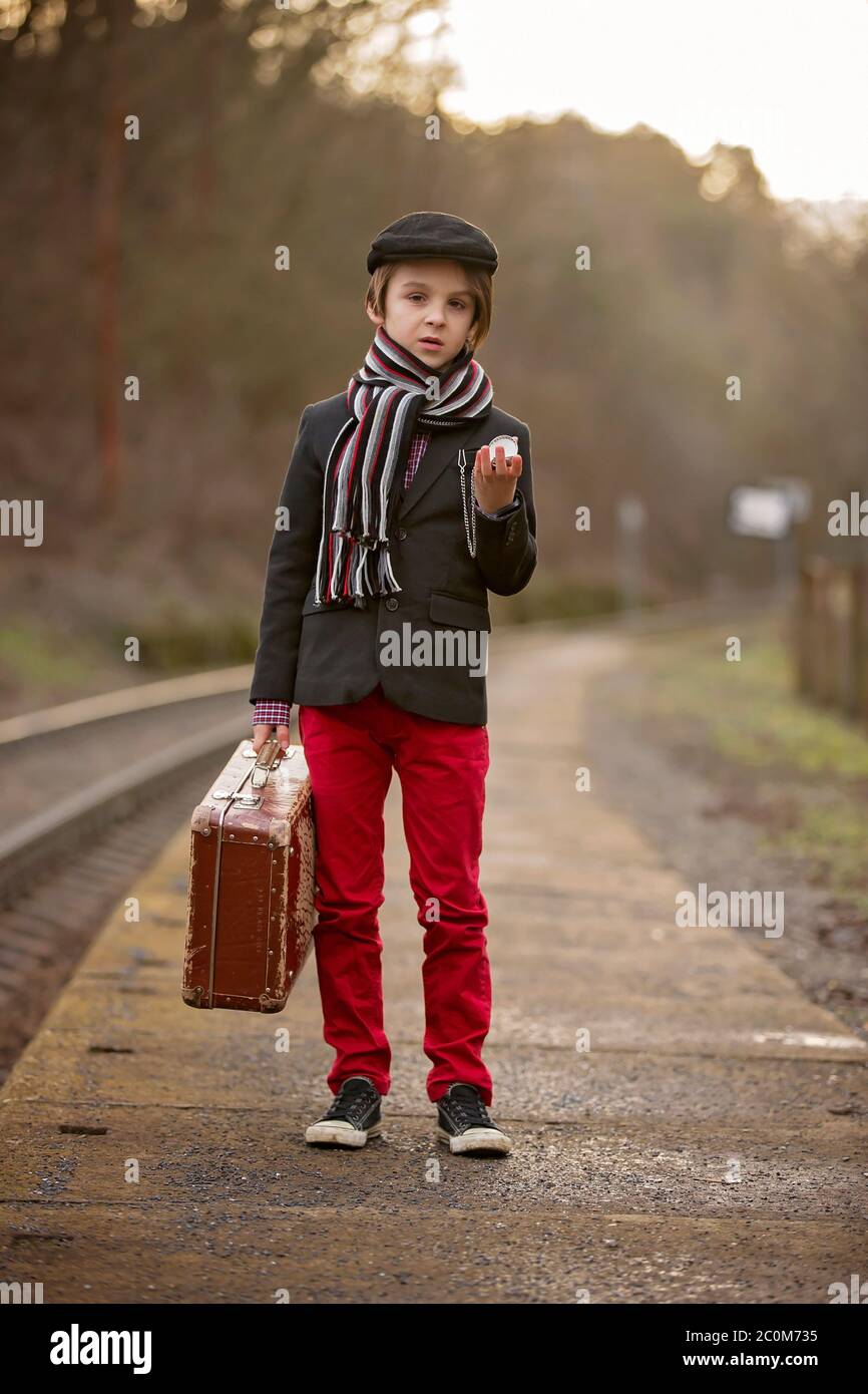 Adorable boy on a railway station, waiting for the train with vintage ...