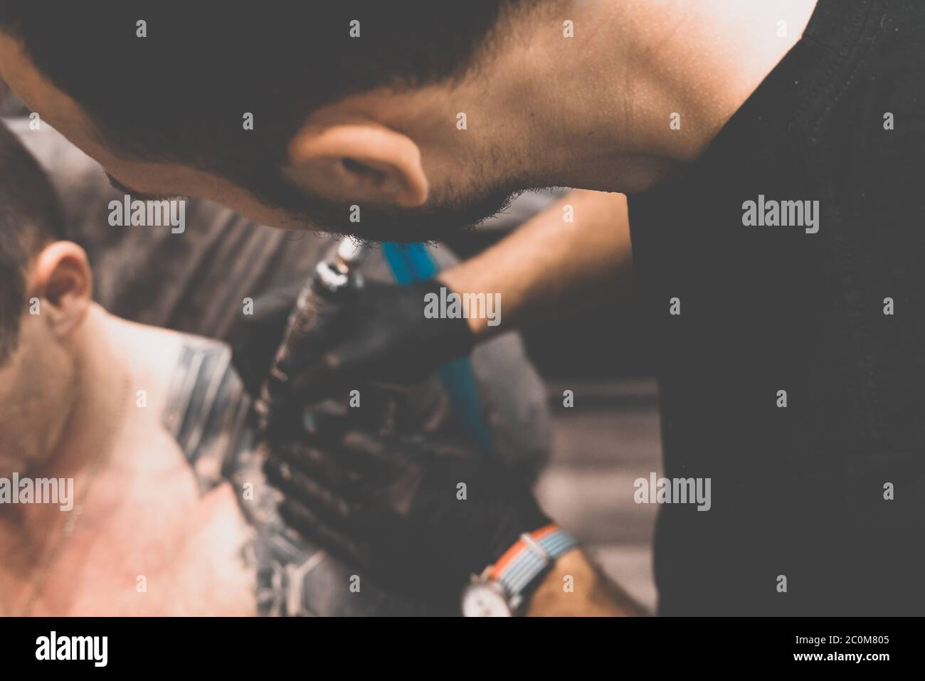 Tattoo salon. The tattoo master is tattooing a man on his shoulder ...