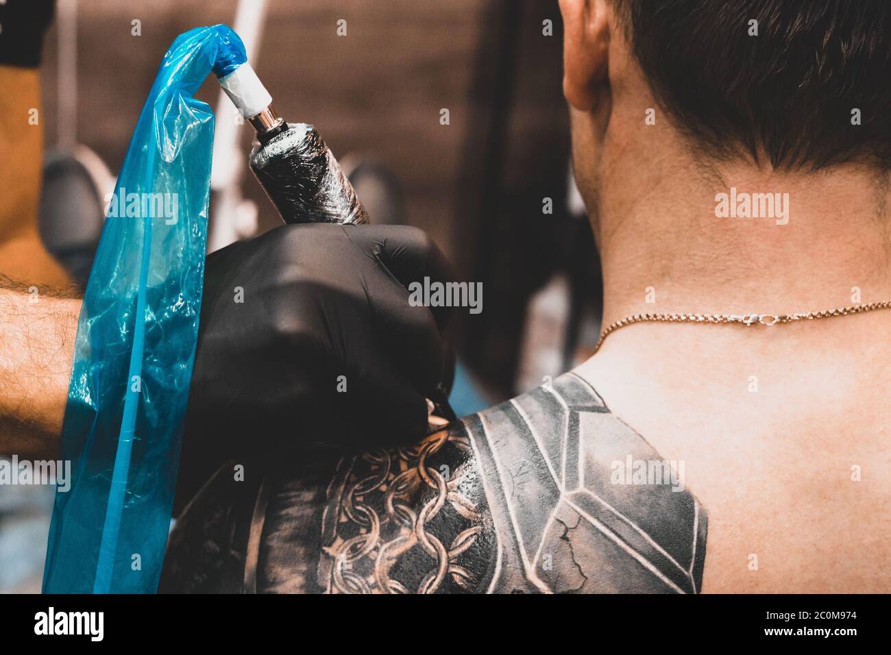 Tattoo salon. The tattoo master is tattooing a man on his shoulder ...