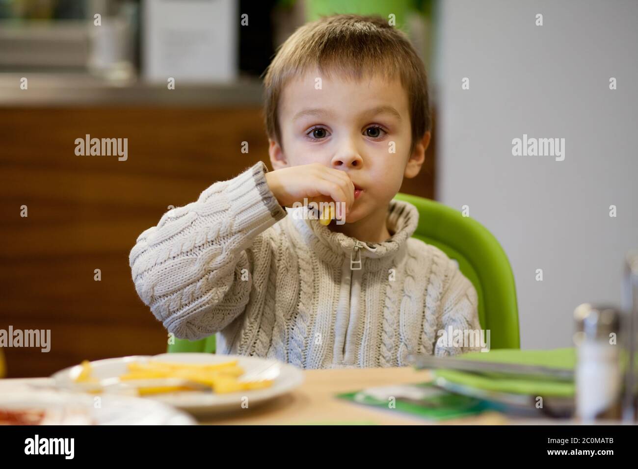 Little toddler boy, eating junk food in restaurant Stock Photo - Alamy
