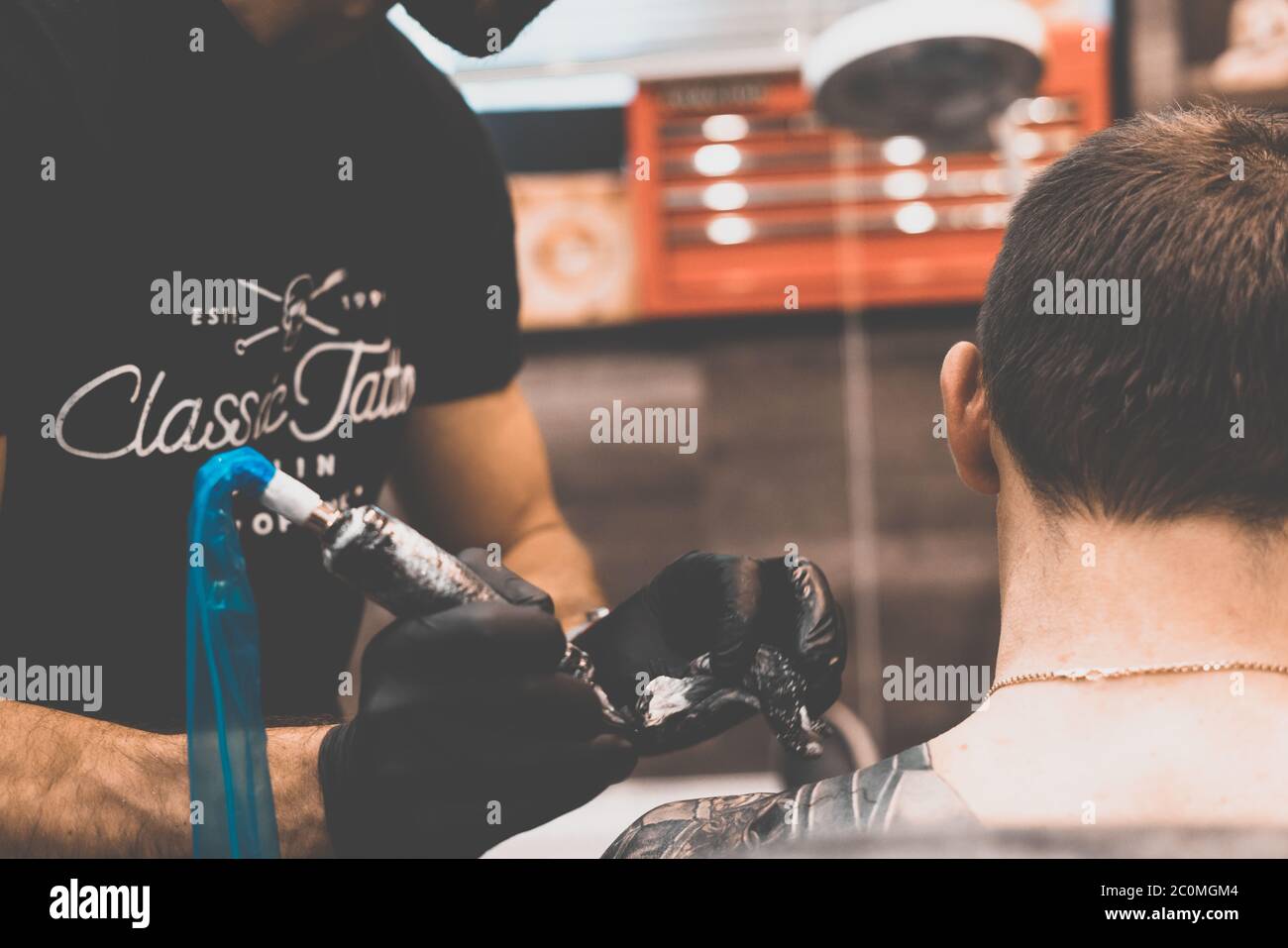 Tattoo salon. The tattoo master is tattooing a man on his shoulder ...