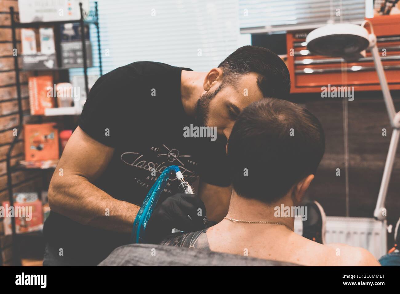 Tattoo salon. The tattoo master is tattooing a man on his shoulder ...