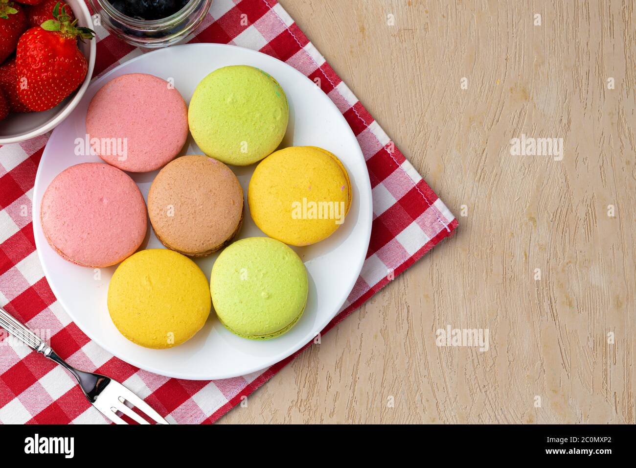French macaroon cookies of bright colors served in white ceramic plate ...
