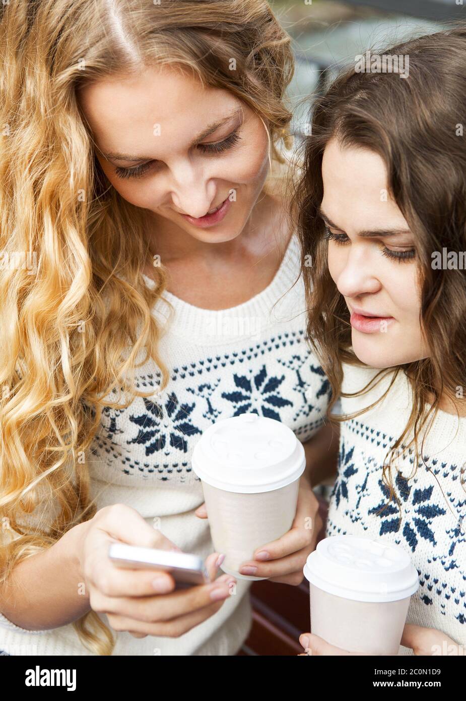 Two Happy Female Friends Sharing Social Media In A Smart Phone Outdoors
