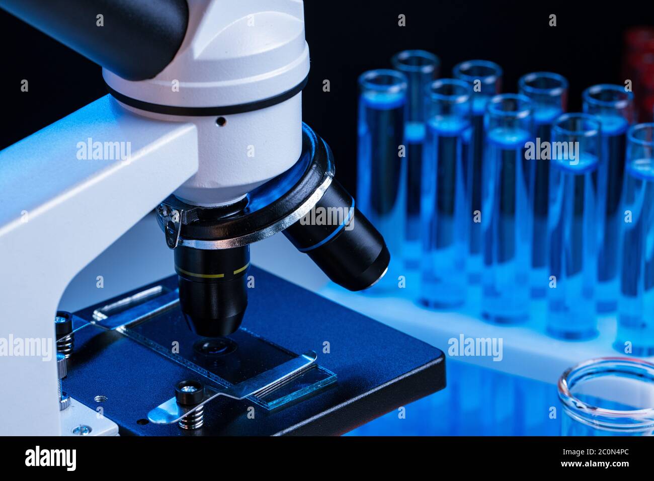 Close up of laboratory microscope with set of test tubes with blue ...