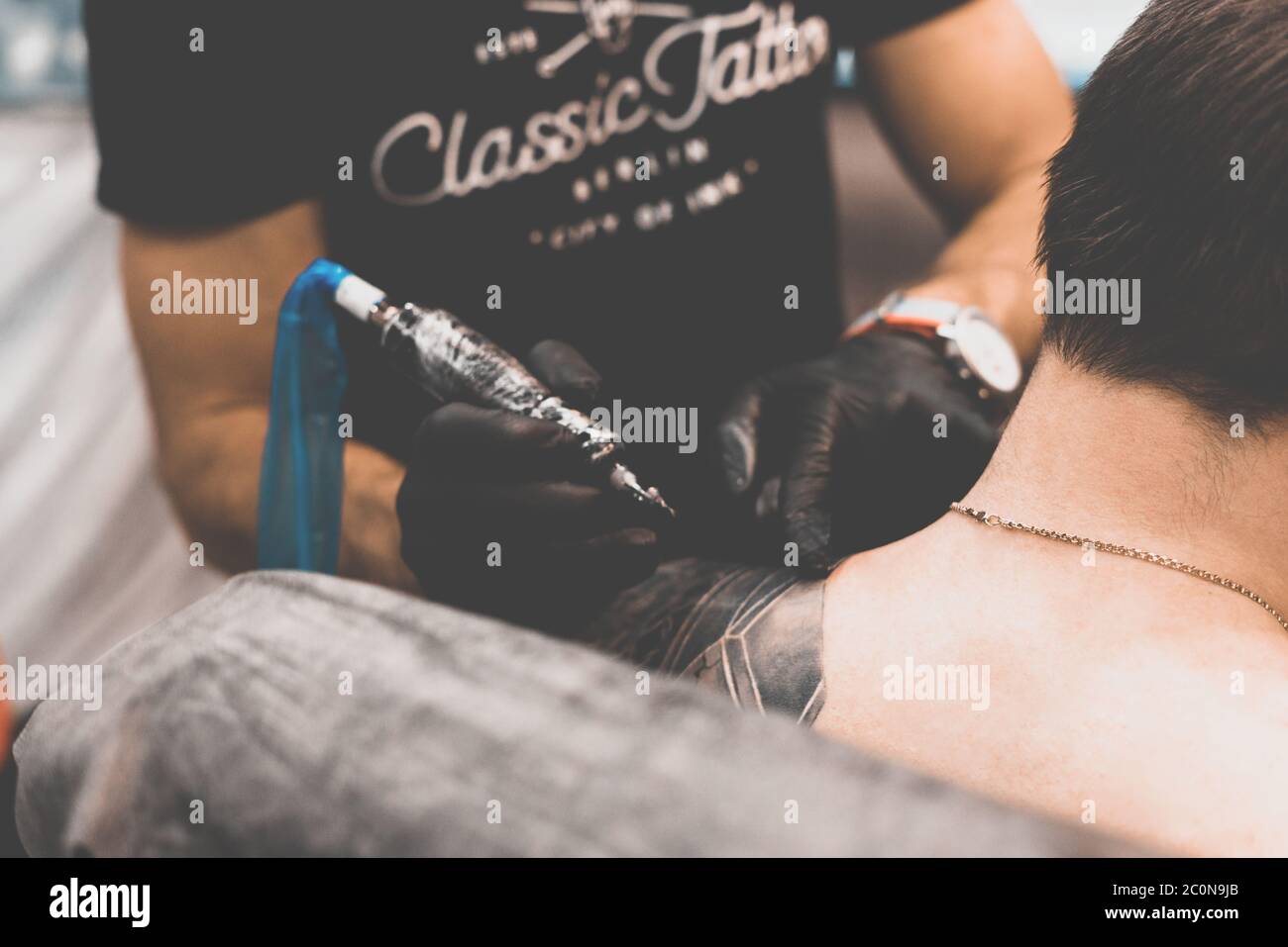 Tattoo salon. The tattoo master is tattooing a man on his shoulder ...
