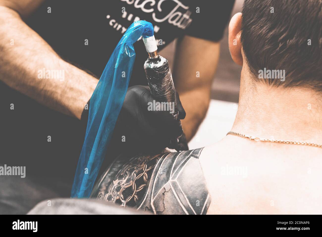 Tattoo salon. The tattoo master is tattooing a man on his shoulder ...