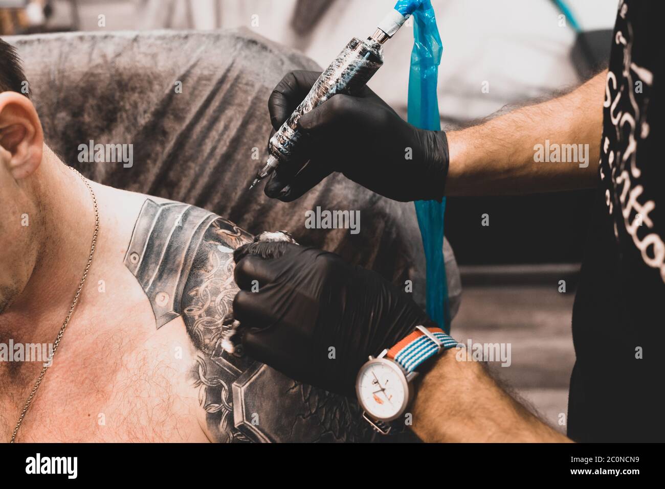 Tattoo salon. The tattoo master is tattooing a man on his shoulder ...