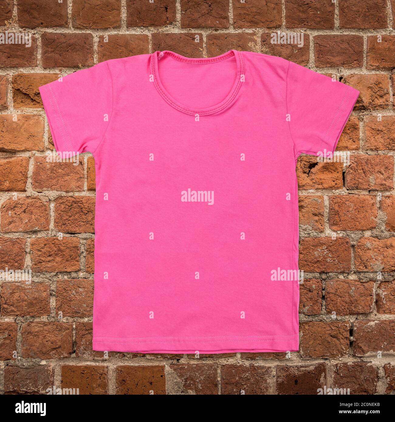 Pink blank t-shirt on dark brick background Stock Photo - Alamy