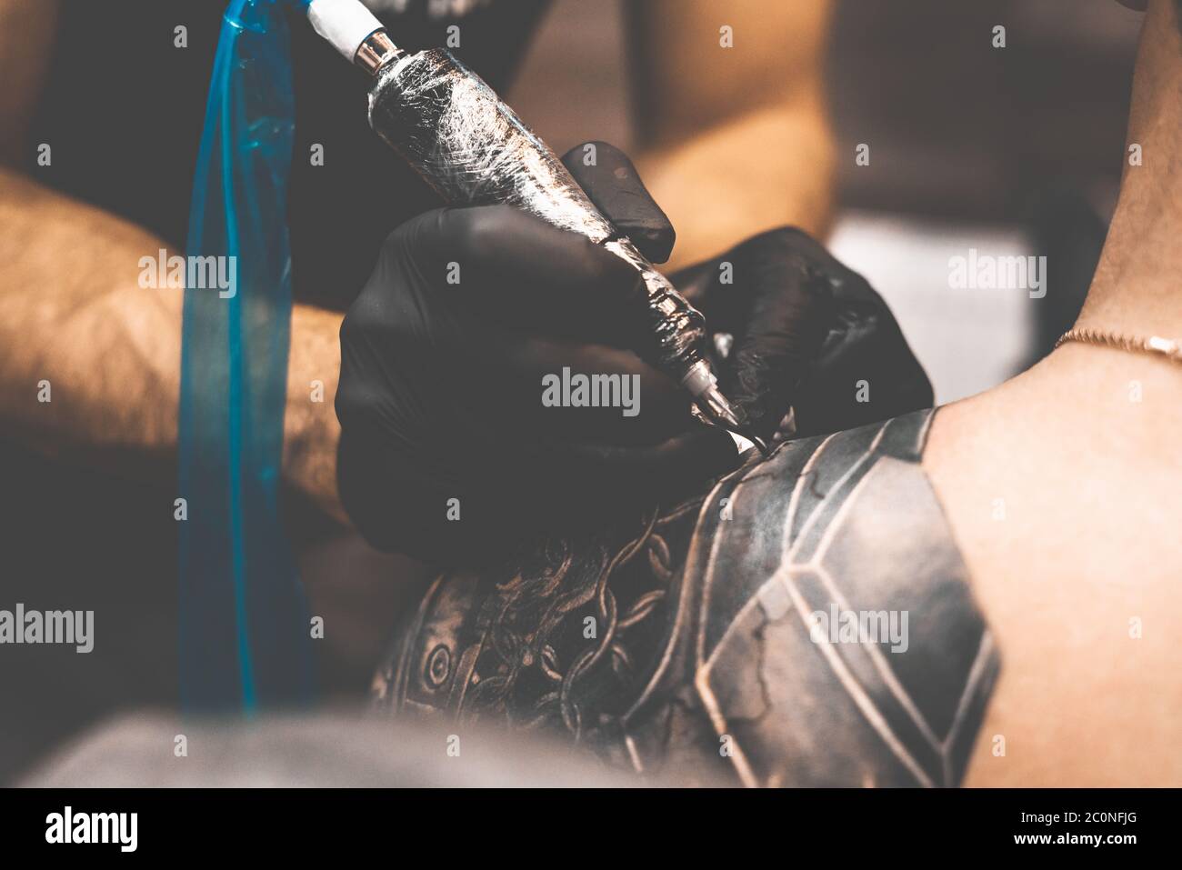 Tattoo salon. The tattoo master is tattooing a man on his shoulder ...