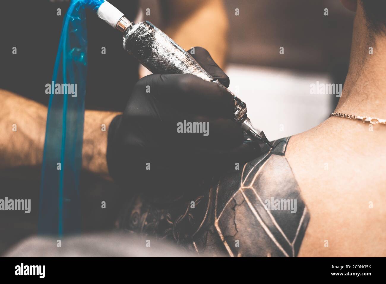 Tattoo salon. The tattoo master is tattooing a man on his shoulder ...