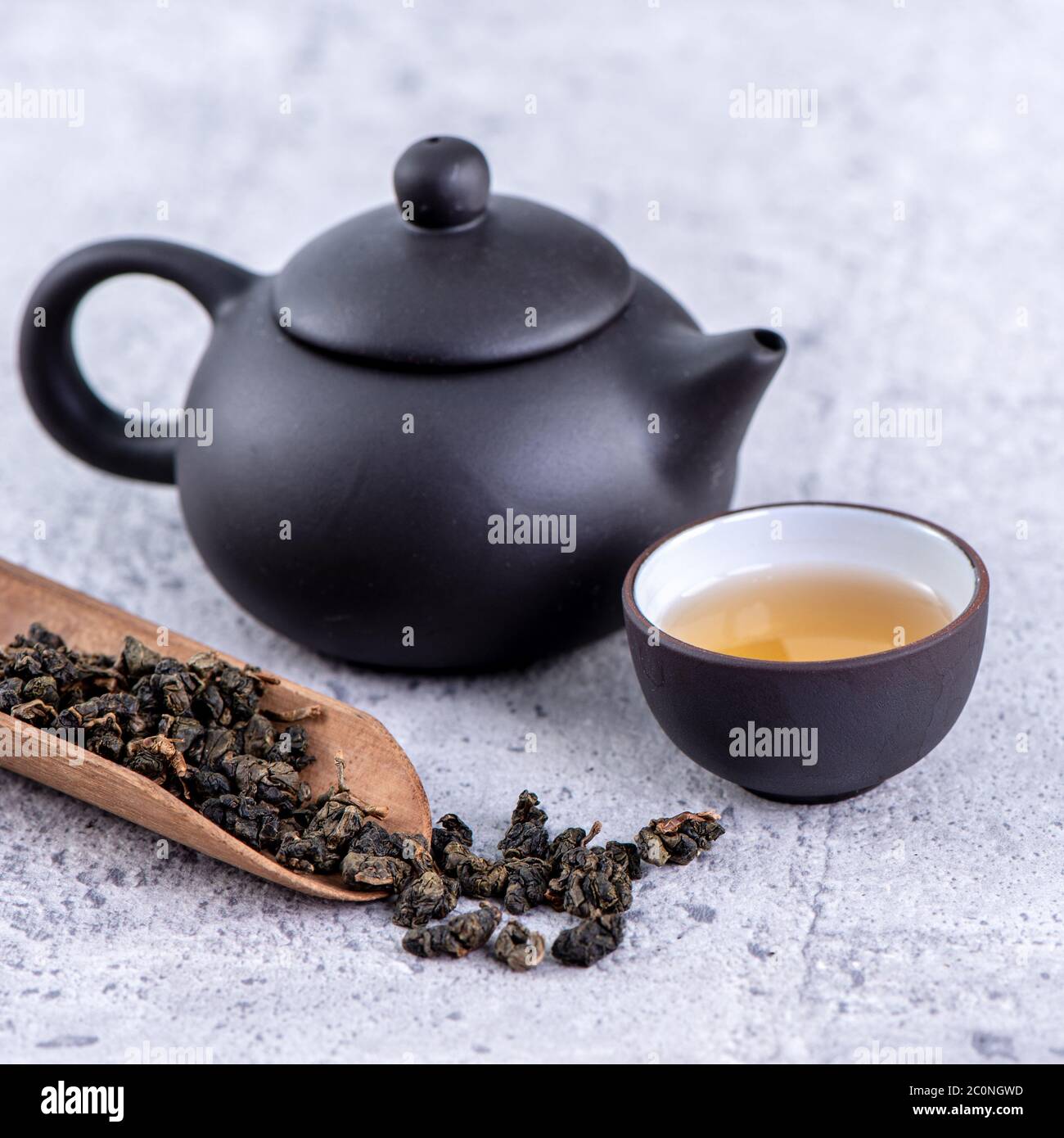 Hot tea in black teapot and cups and dry tea leaves over bright gray ...