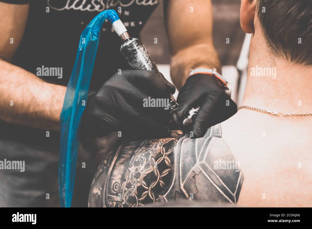 Tattoo salon. The tattoo master is tattooing a man on his shoulder ...
