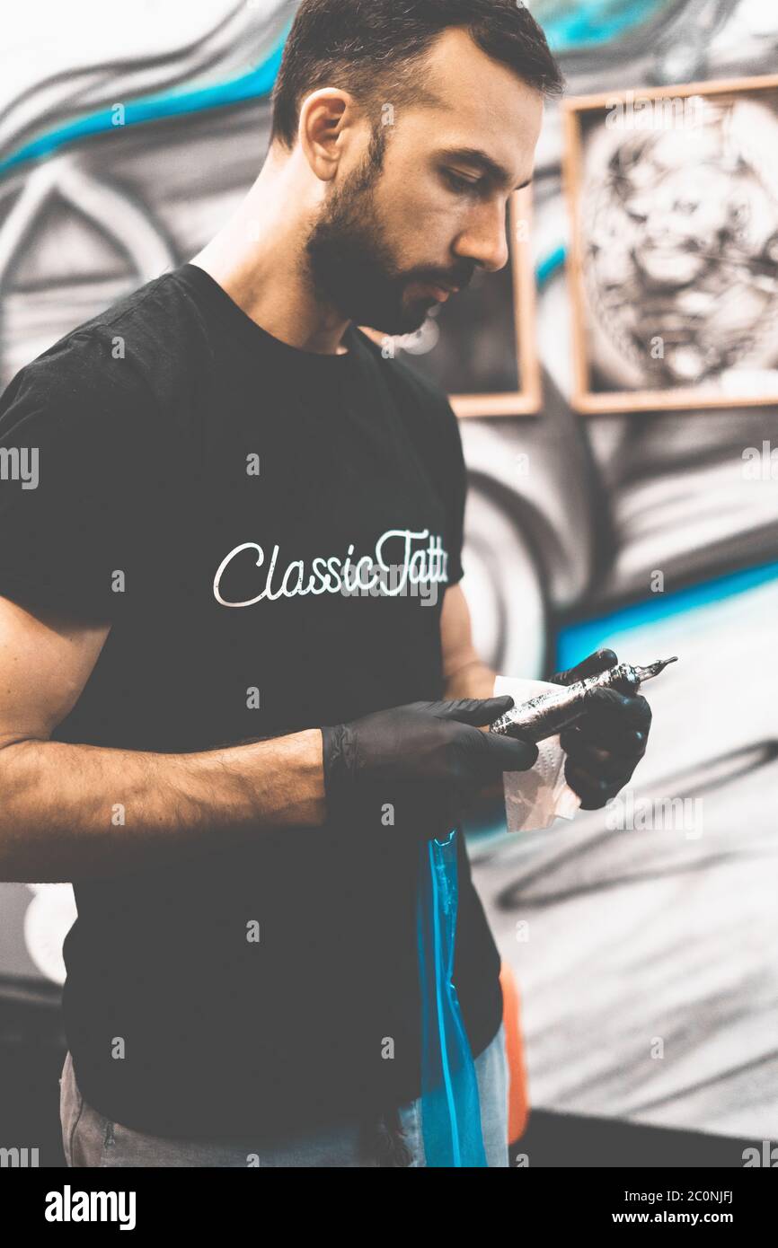 Tattoo salon. The tattoo master is tattooing a man on his shoulder ...