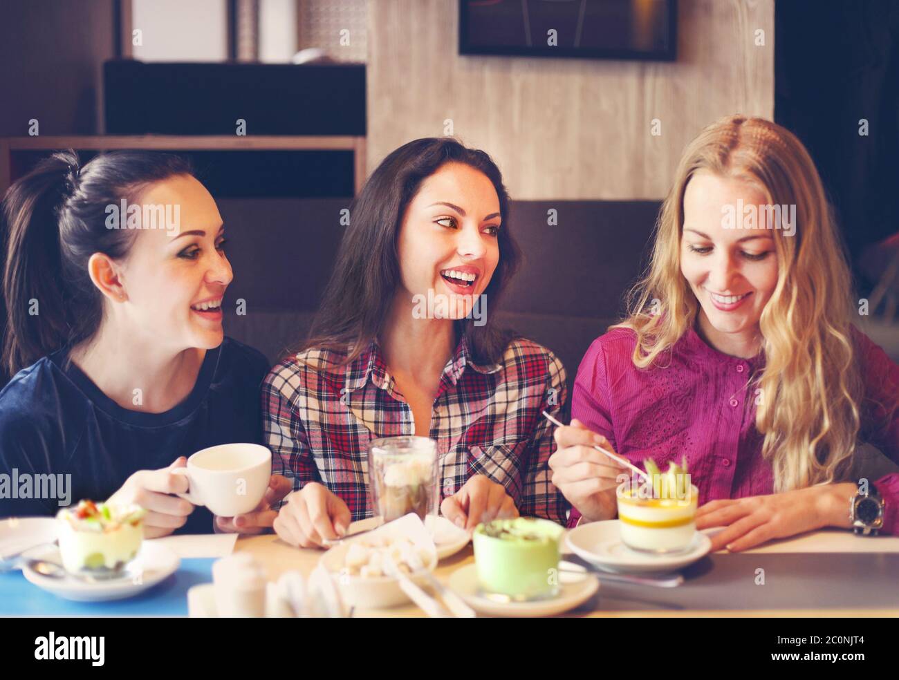 Three young women at a meeting in a cafe Stock Photo - Alamy