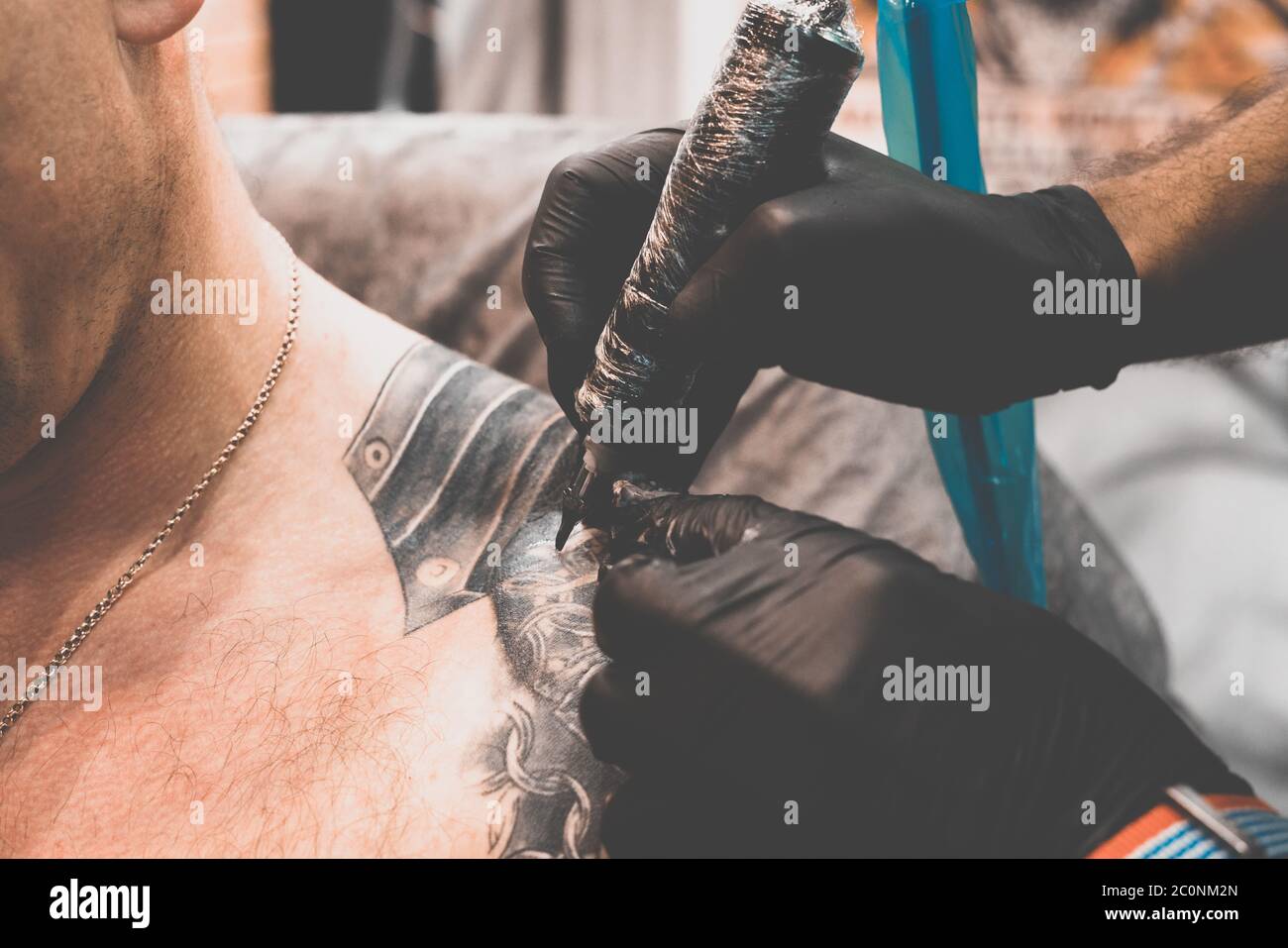 Tattoo salon. The tattoo master is tattooing a man on his shoulder ...