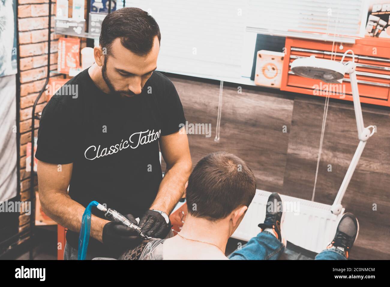Tattoo salon. The tattoo master is tattooing a man on his shoulder ...