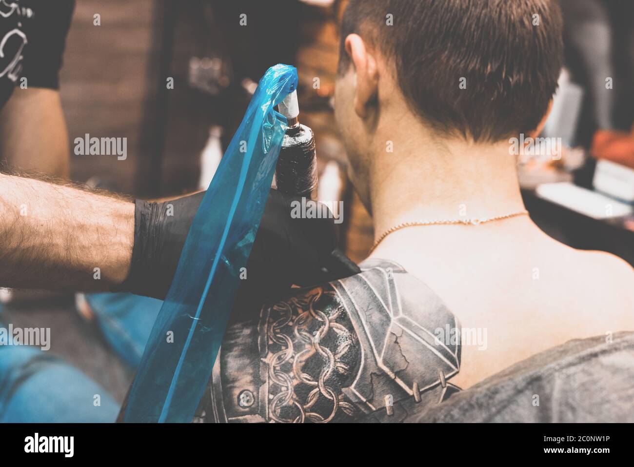 Tattoo salon. The tattoo master is tattooing a man on his shoulder ...