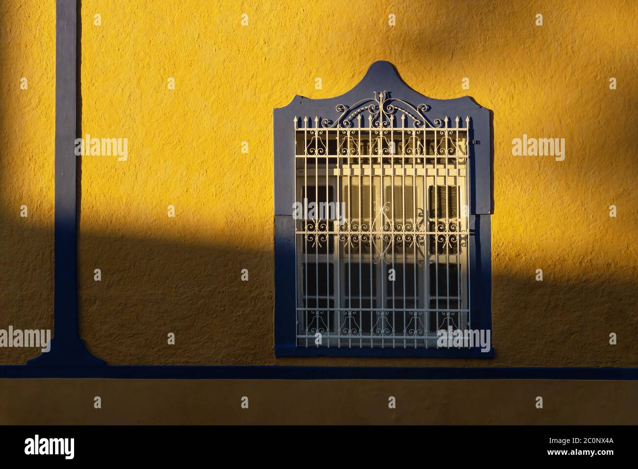 Sunlit facade of colorful colonial window with beautiful shadows in ...