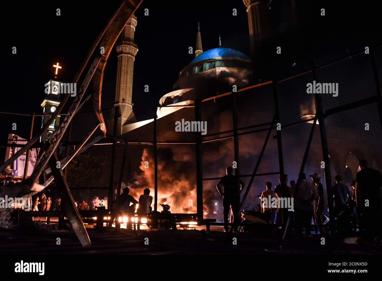 Beirut, Lebanon, 11 June 2020. People look on as a fire burns in front ...