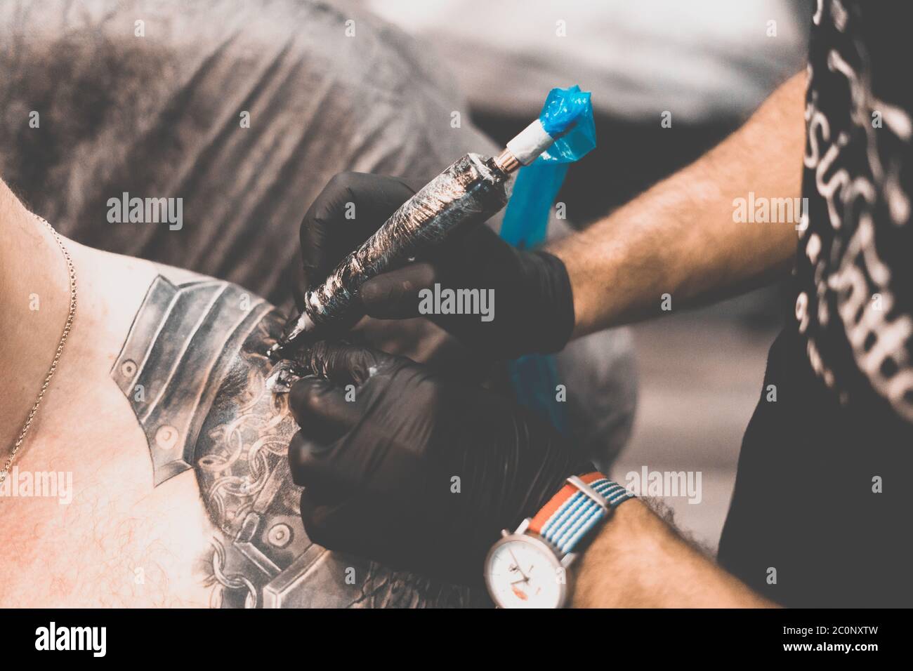 Tattoo salon. The tattoo master is tattooing a man on his shoulder ...