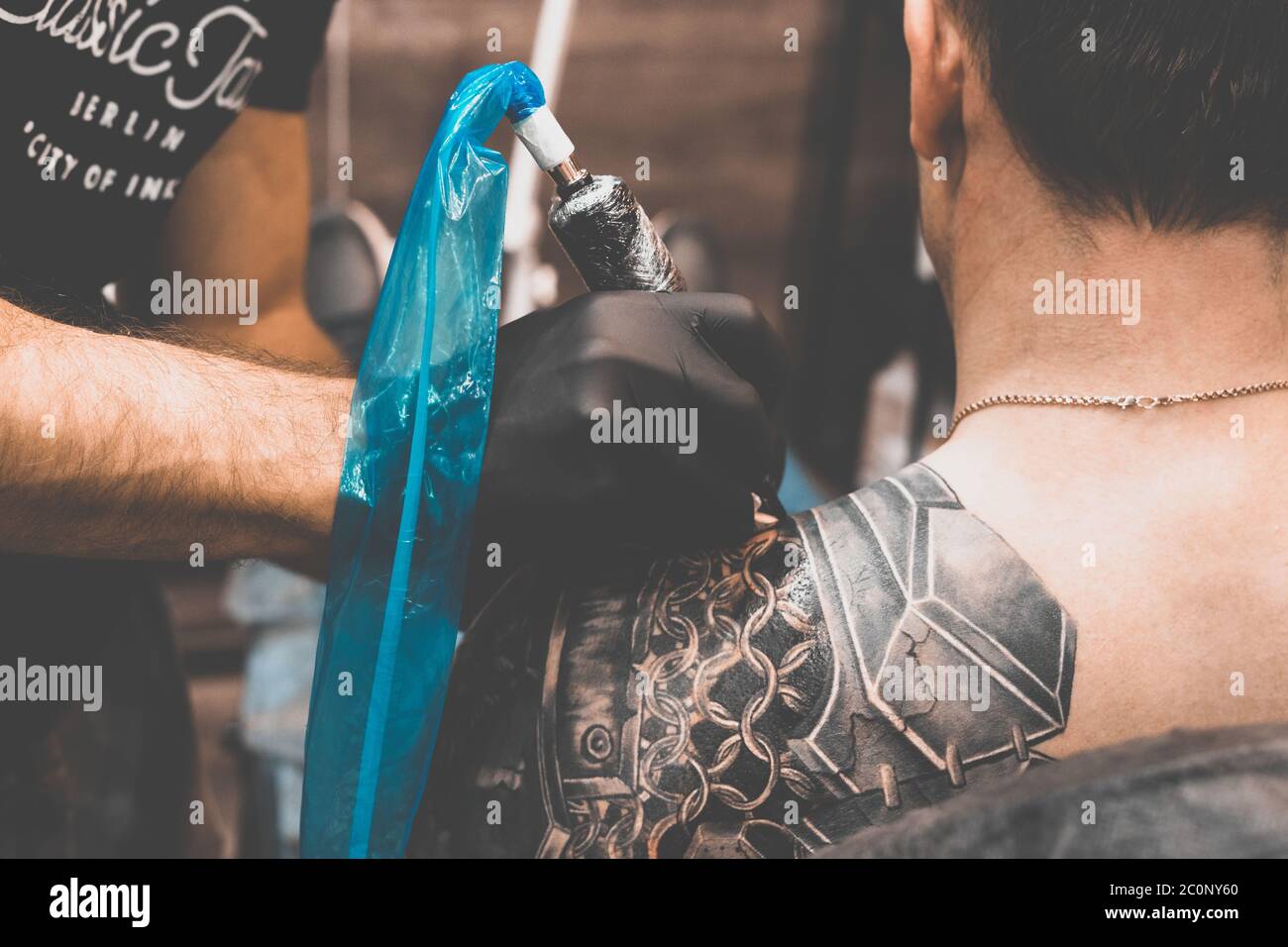 Tattoo salon. The tattoo master is tattooing a man on his shoulder ...