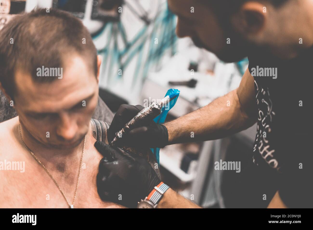 Tattoo salon. The tattoo master is tattooing a man on his shoulder ...