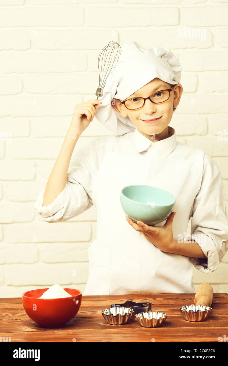 young boy small cute cook chef in white uniform and hat on smiling face ...