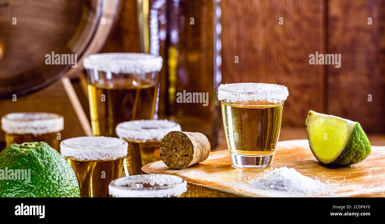 glass of tequila on rustic table, distilled drink with lemon, salt and ...