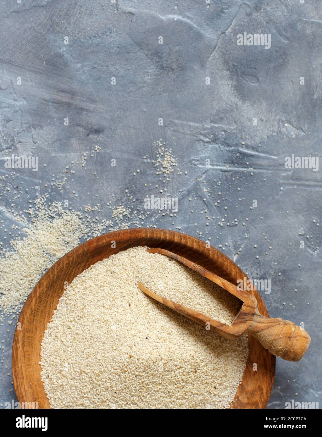 Raw uncooked fonio seeds with a spoon on grey background top view with ...